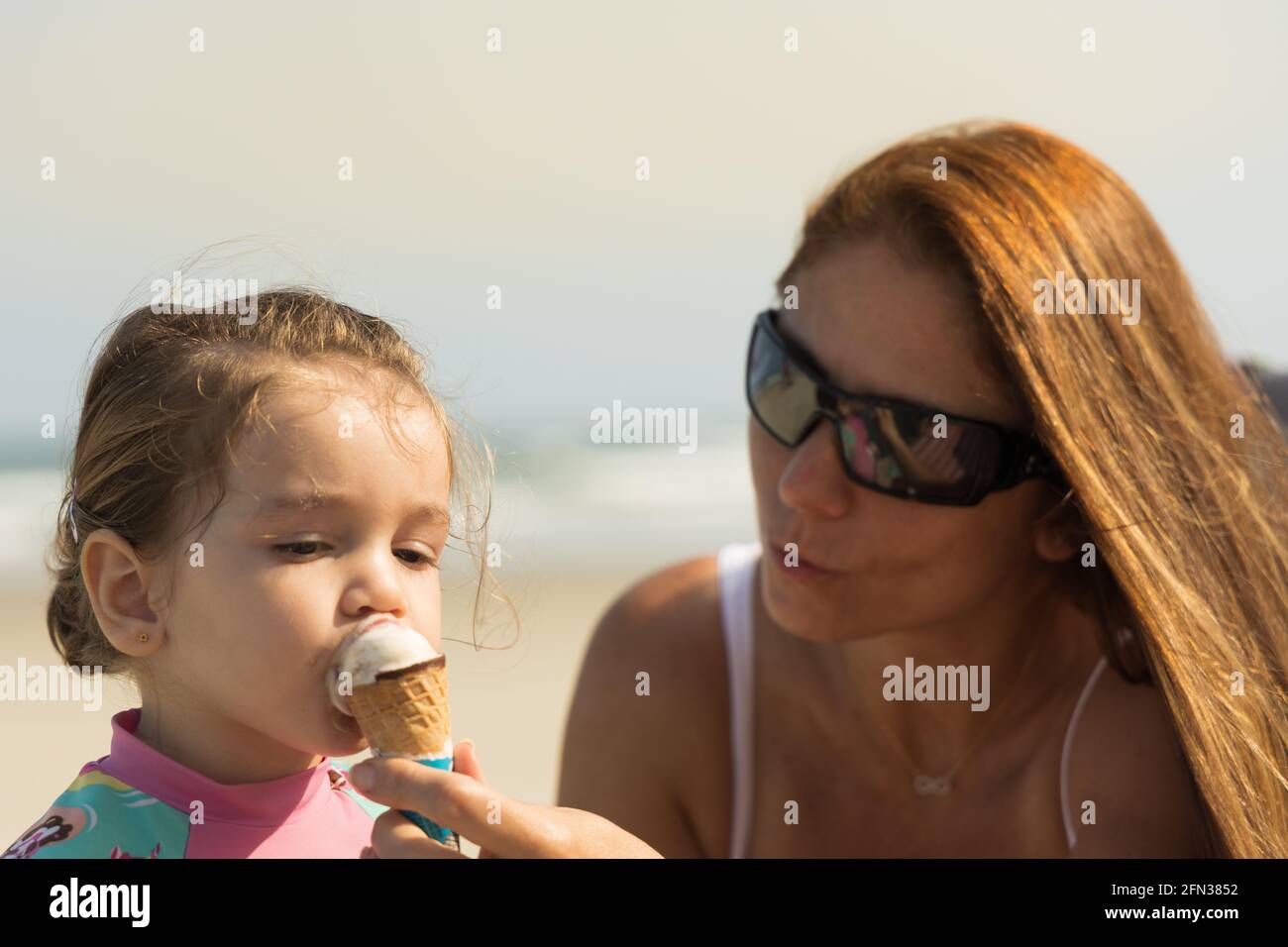 mother giving ice cream to her daughter on the beach Stock Photo - Alamy