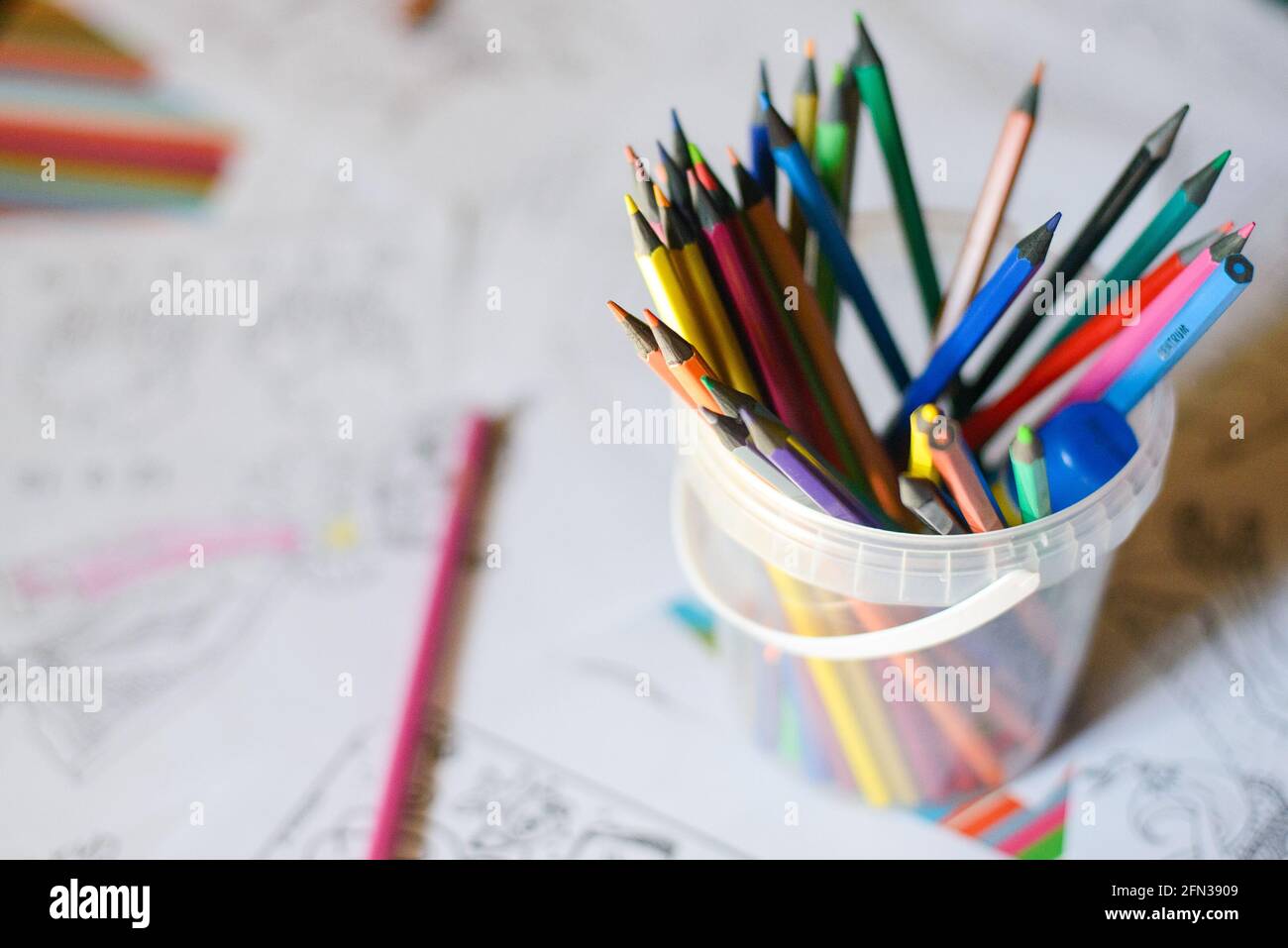 Colorful pencils in bucket with with drawings in blurred background ...