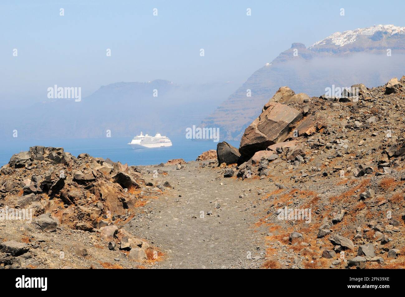 Textured look of volcano surface with blurred cruise ship in background ...