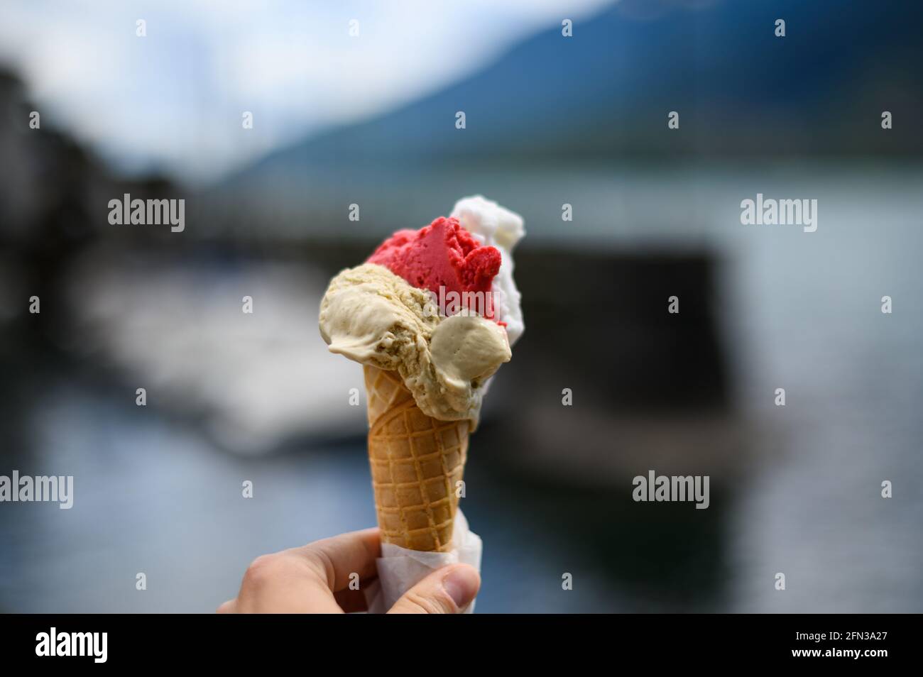 Italian ice cream with waffle cone in hand with pistachio, strawberry ...