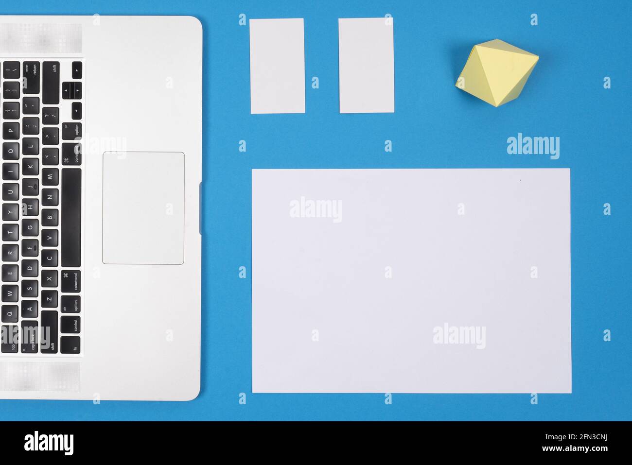 Top view of a laptop with blank pieces of paper for your text on blue ...