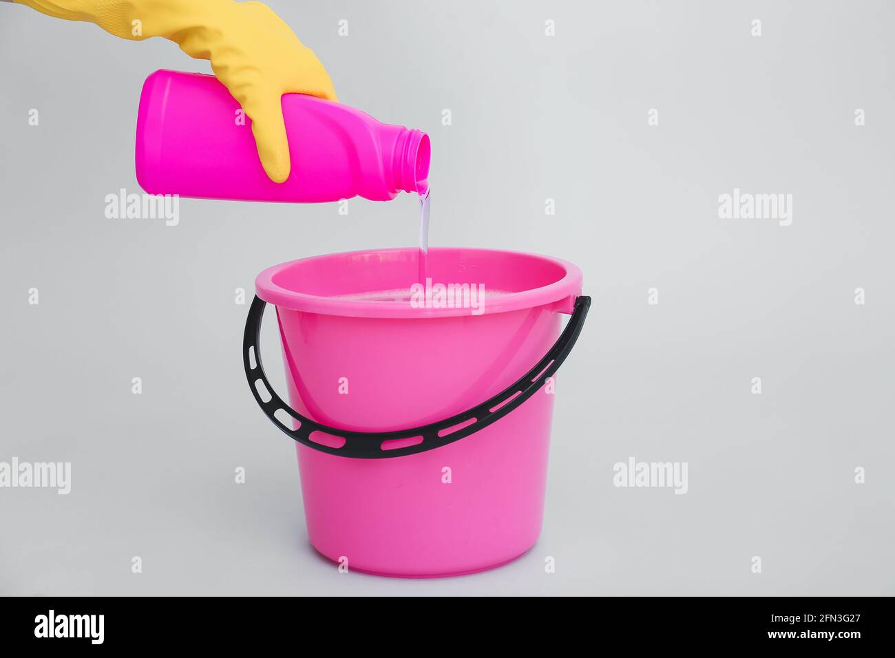 Woman pouring detergent into bucket on light background Stock Photo - Alamy