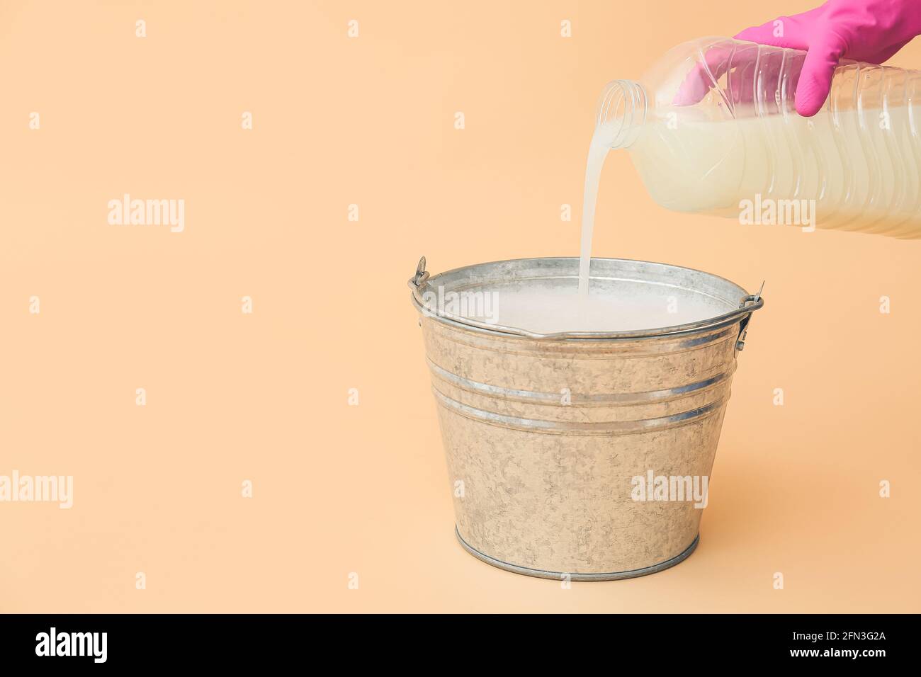 Woman pouring detergent into bucket on color background Stock Photo - Alamy