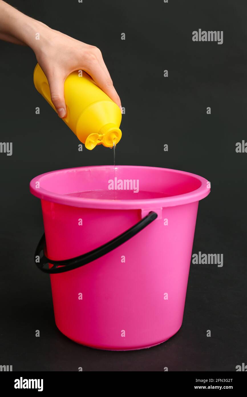 Woman pouring detergent into bucket on dark background Stock Photo - Alamy