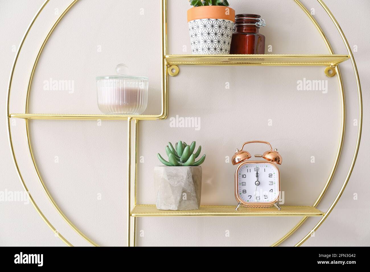 Shelf with alarm clock and decor hanging on light wall Stock Photo - Alamy