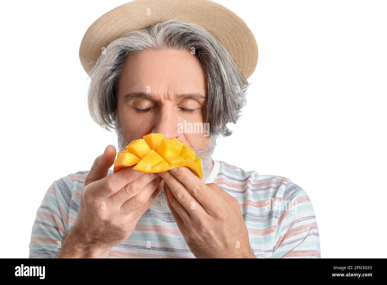 Senior man eating fresh mango on white background Stock Photo - Alamy