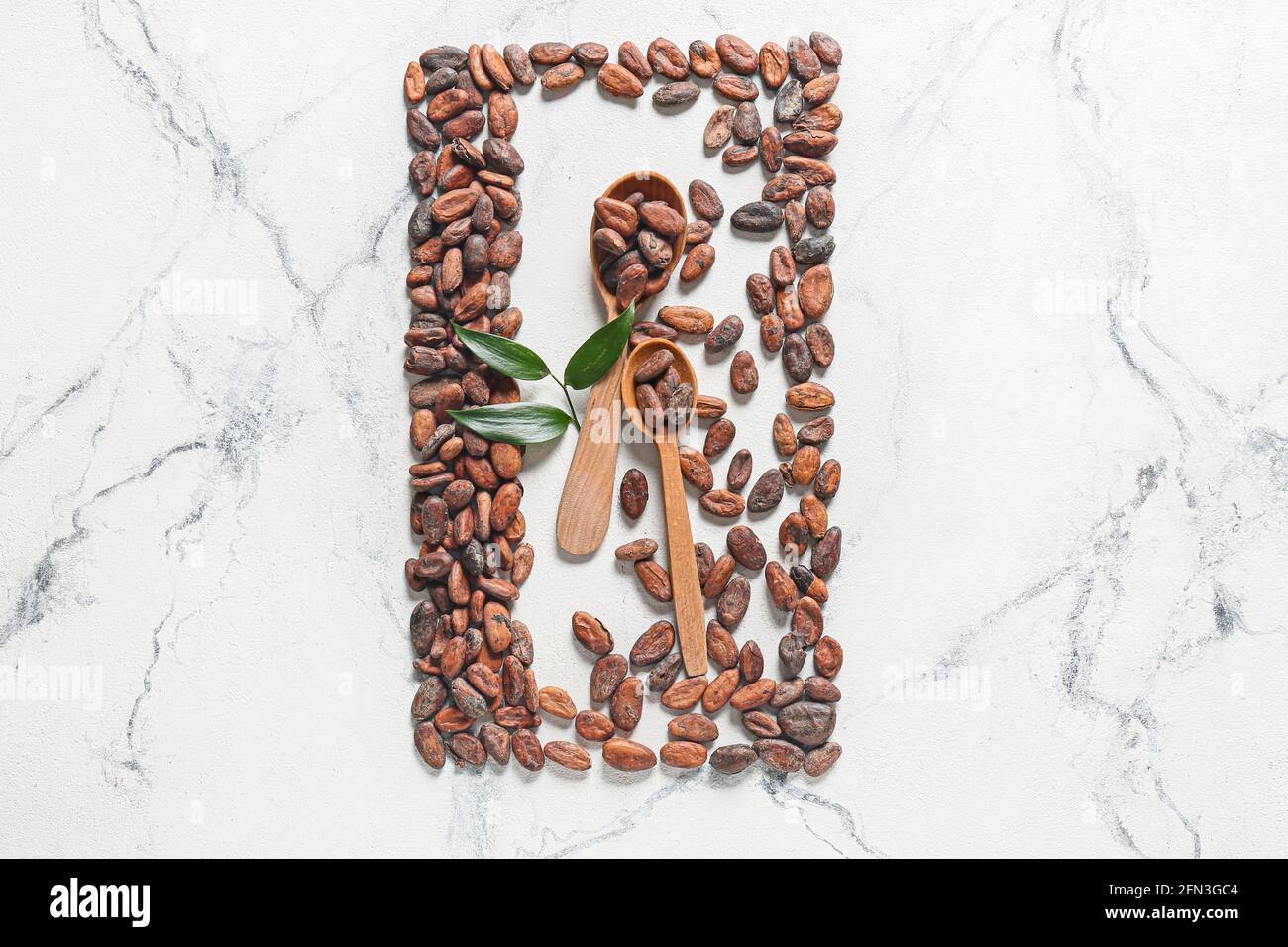Spoons with cocoa beans on light background Stock Photo - Alamy