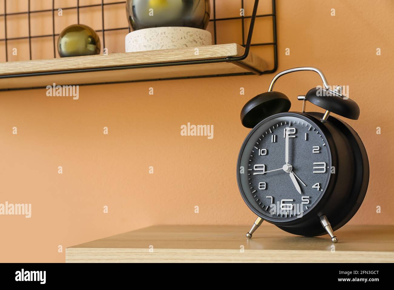 Shelf with alarm clock hanging on color wall Stock Photo - Alamy