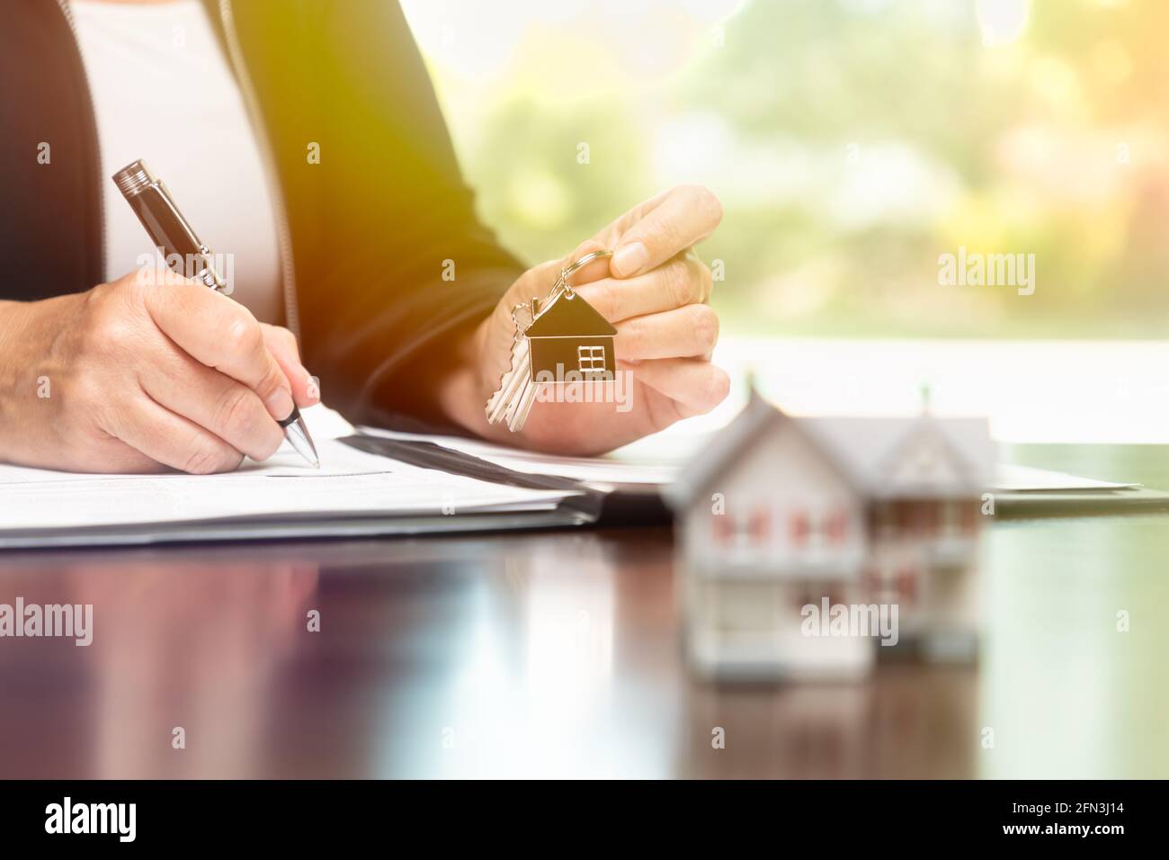 Woman signing real estate contract papers holding house keys and home ...