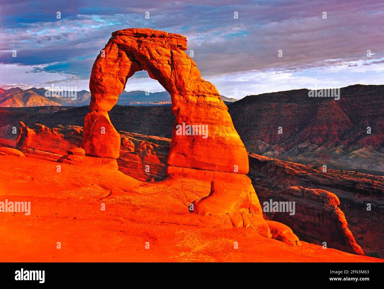 Sunset at Delicate Arch with rolling Rocky Mountains in background ...