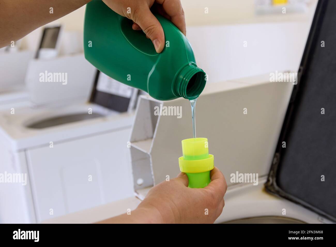 A woman pours liquid powder, pours conditioner, emollient into of the ...