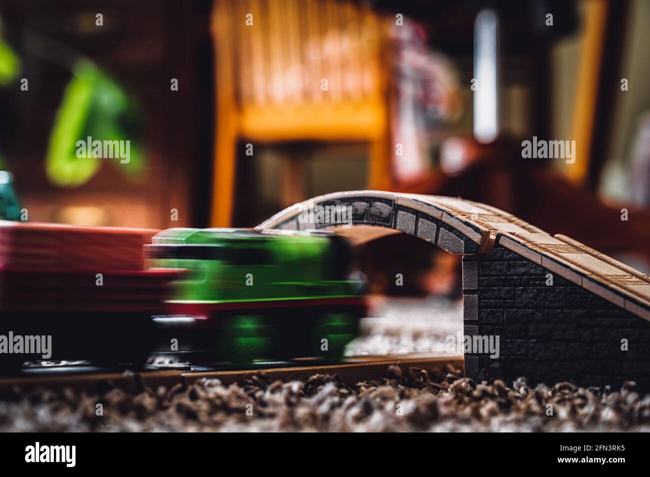 selective focus on wooden toy train track with blurred bridge and ...