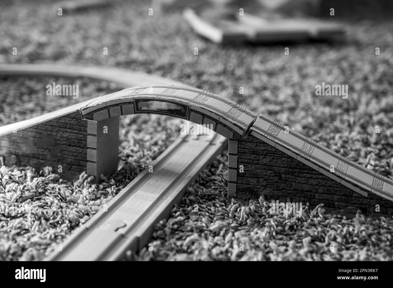 selective focus on wooden toy train track with blurred bridge and ...