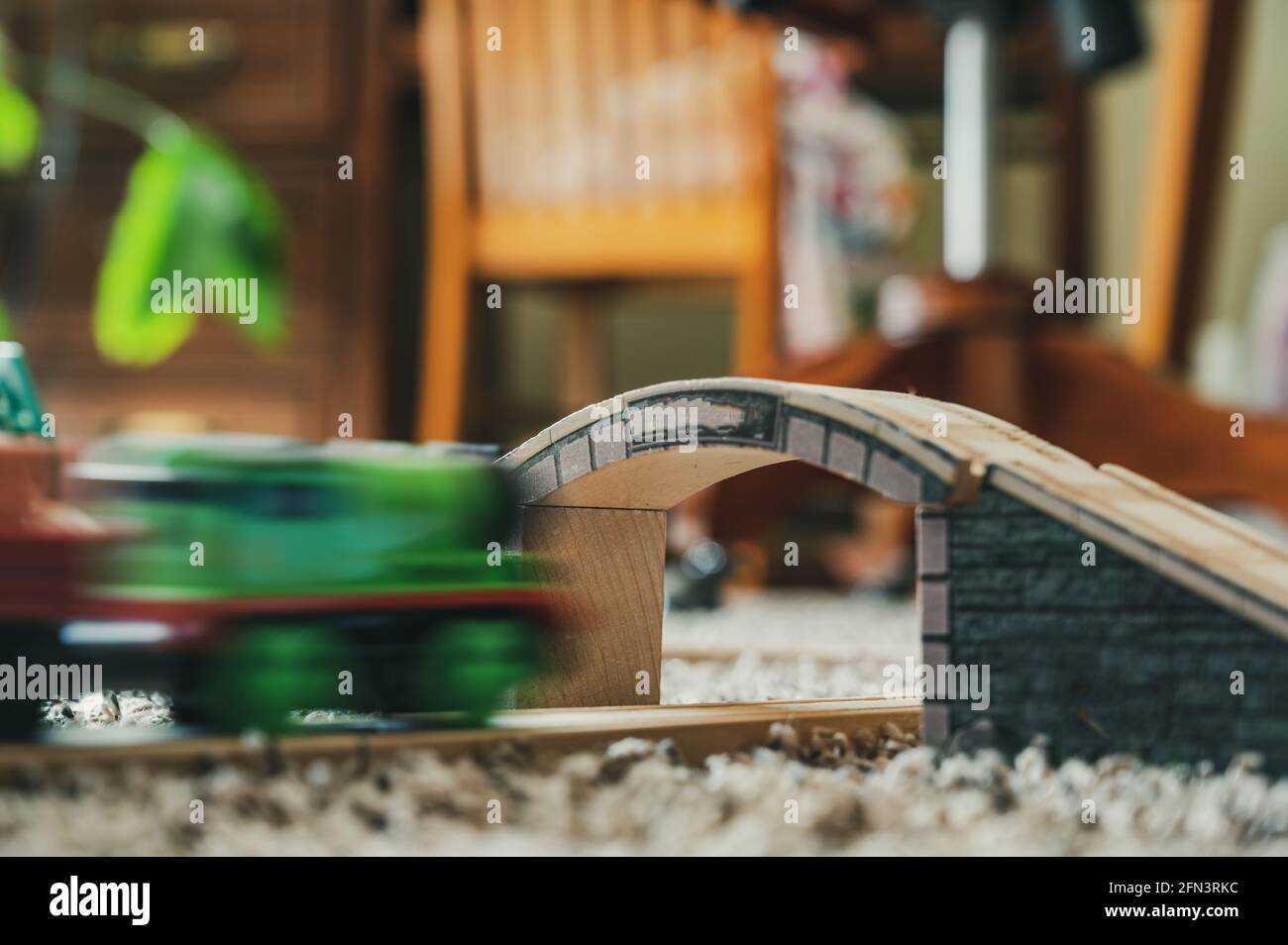 selective focus on wooden toy train track with blurred bridge and ...