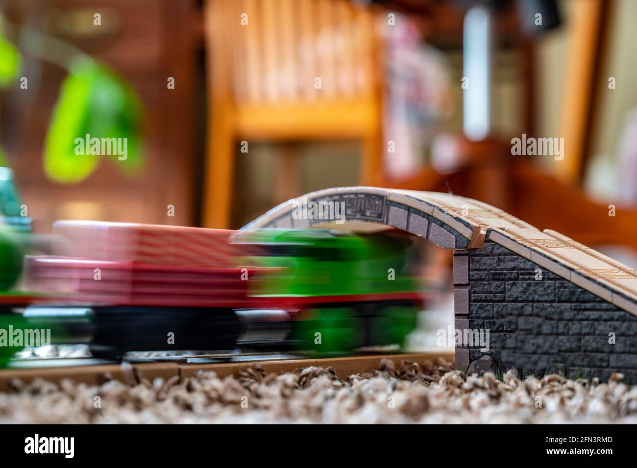 selective focus on wooden toy train track with blurred bridge and ...