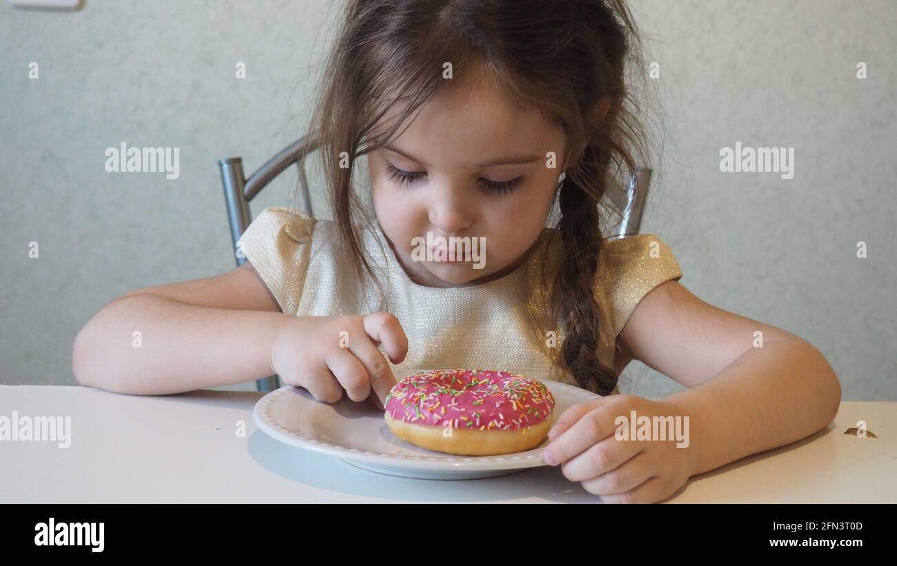 Little happy cute girl is eating donut. child is having fun with donut ...