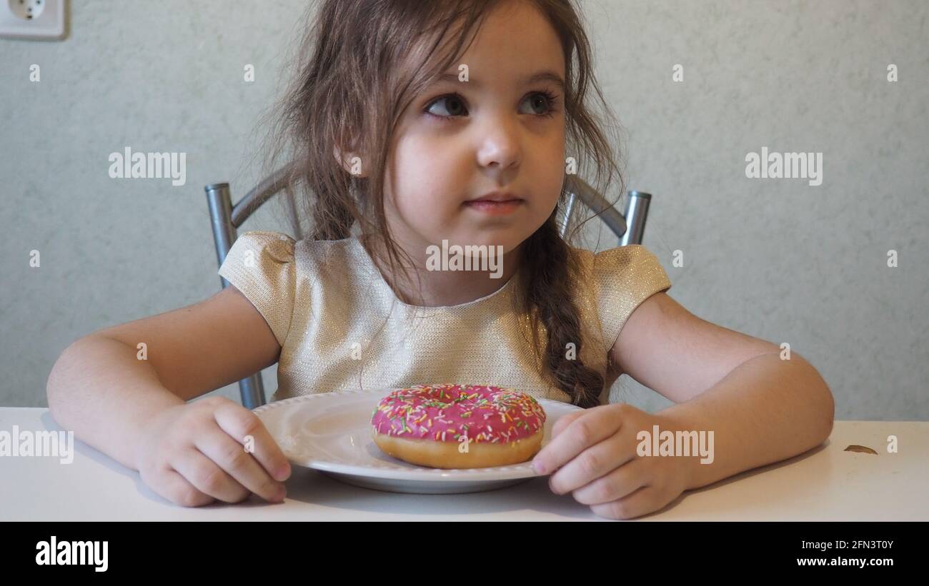 Little happy cute girl is eating donut. child is having fun with donut ...