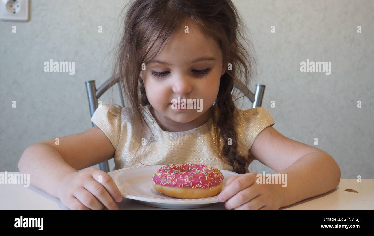Little happy cute girl is eating donut. child is having fun with donut ...