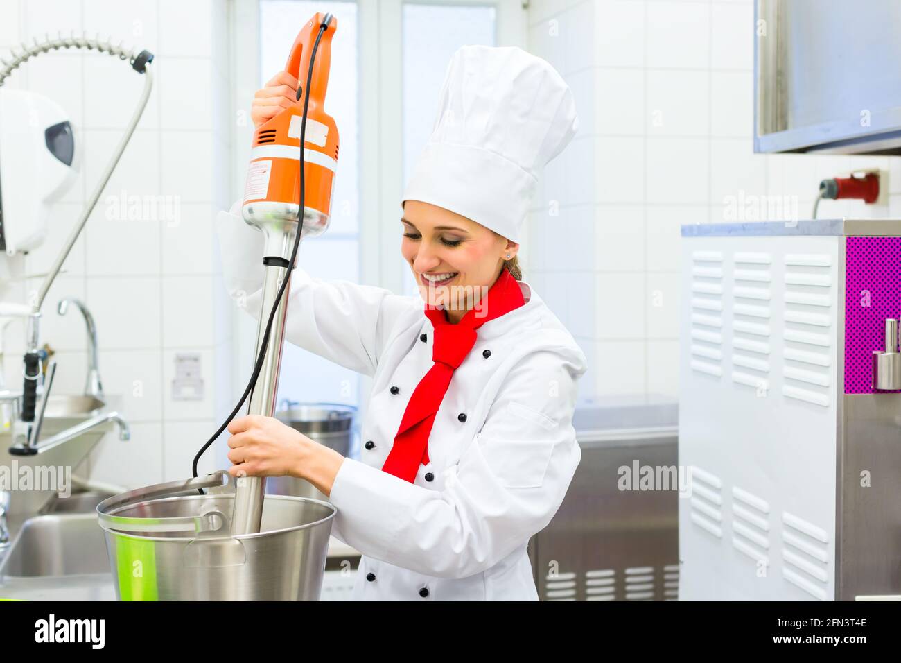 Female Chef preparing ice cream with food processor in gastronomy ...