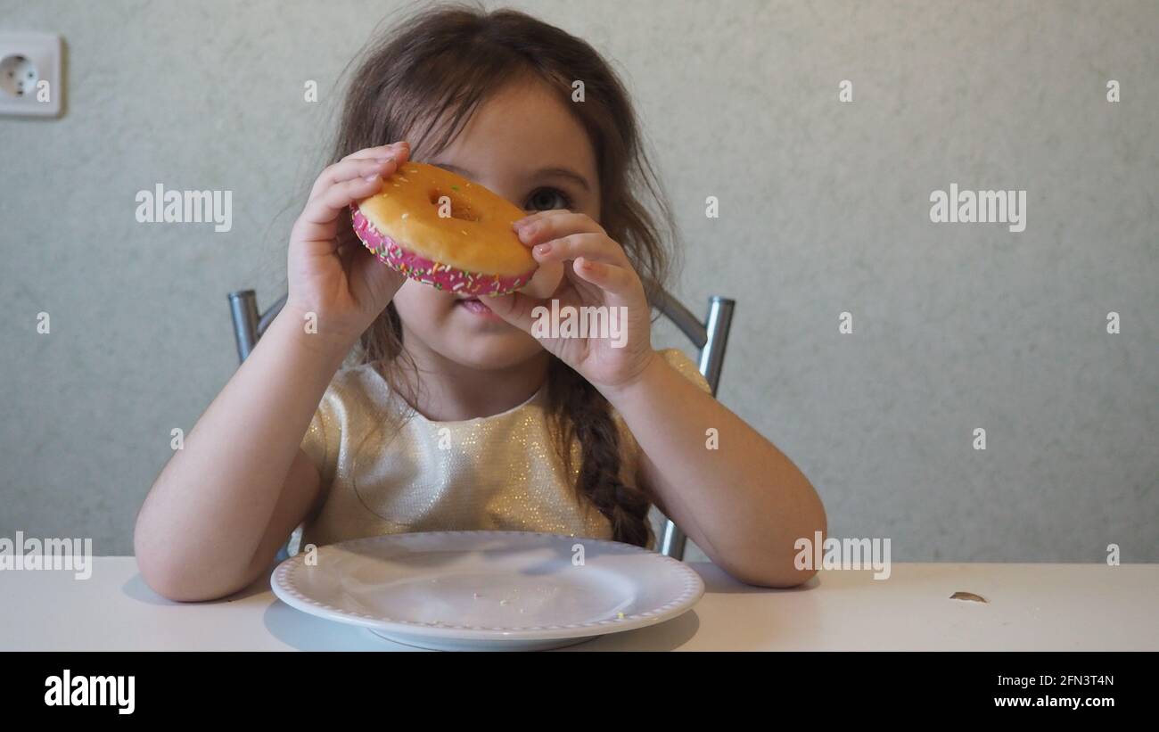 Little happy cute girl is eating donut. child is having fun with donut ...
