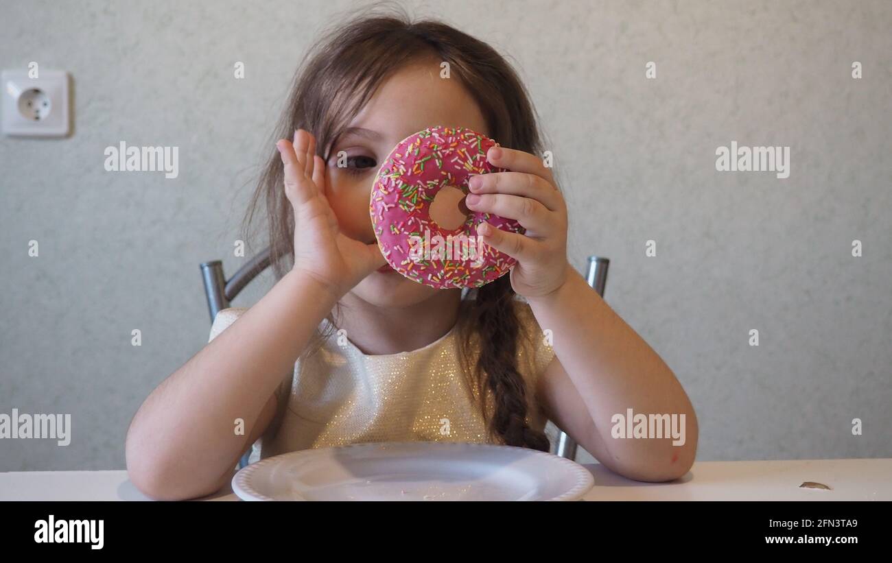 Little happy cute girl is eating donut. child is having fun with donut ...