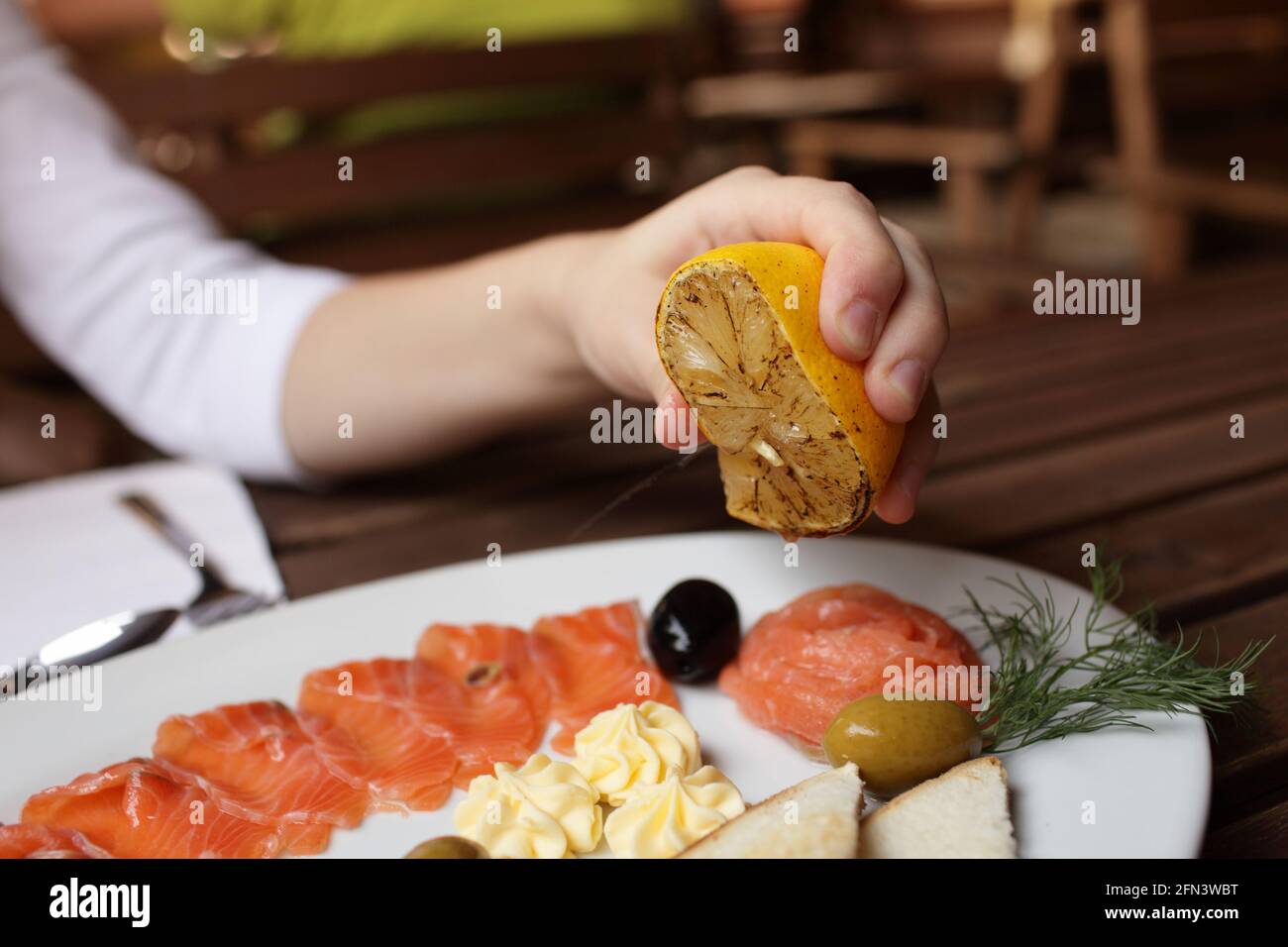 Girl is squeezing lemon on a sliced fish Stock Photo - Alamy