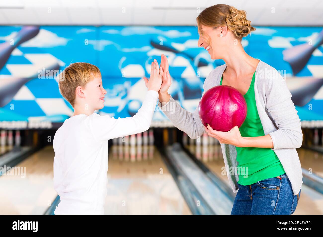 Happy mother and son playing together at bowling center Stock Photo - Alamy