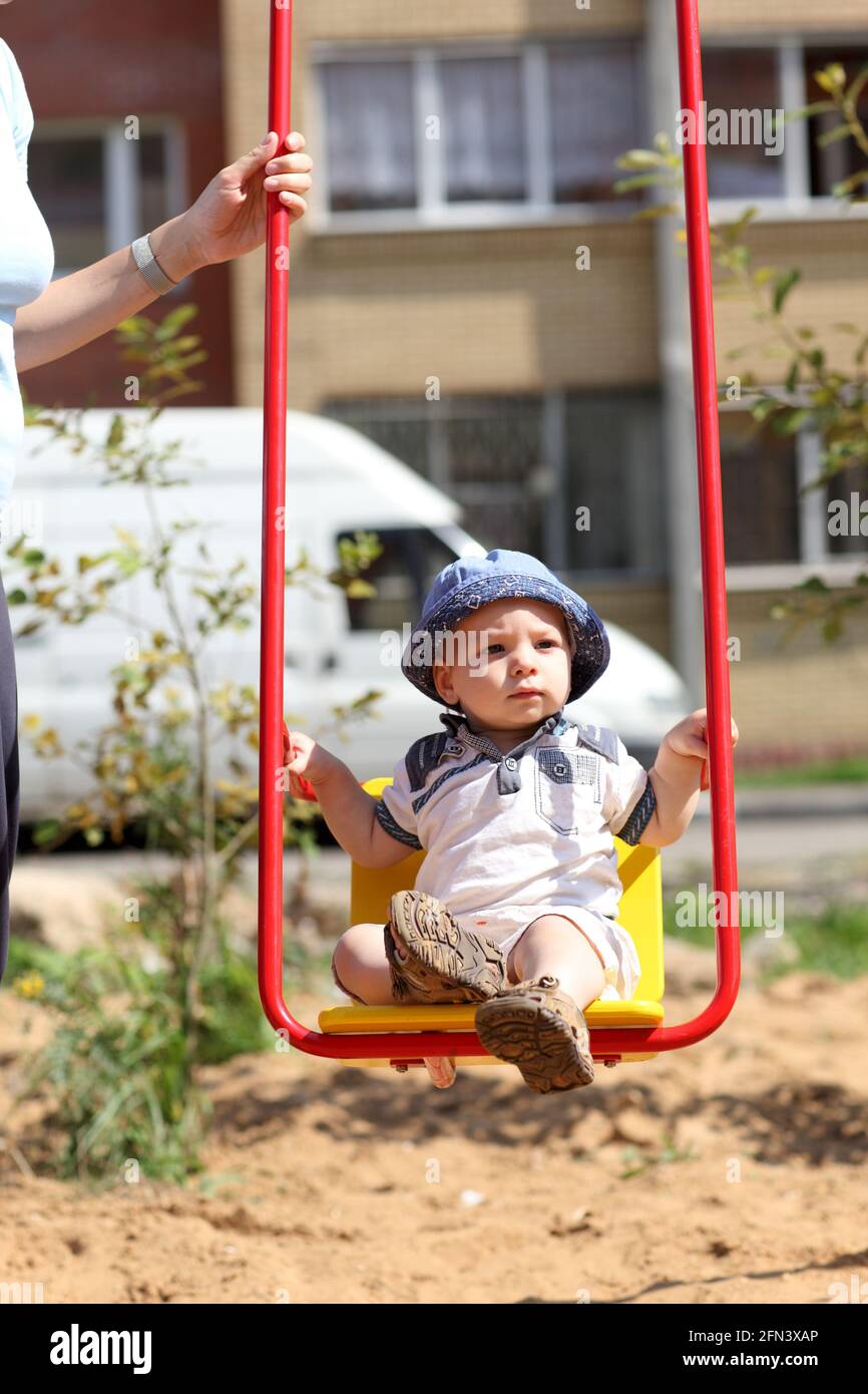 Baby boy is swinging on a swing at playground Stock Photo - Alamy