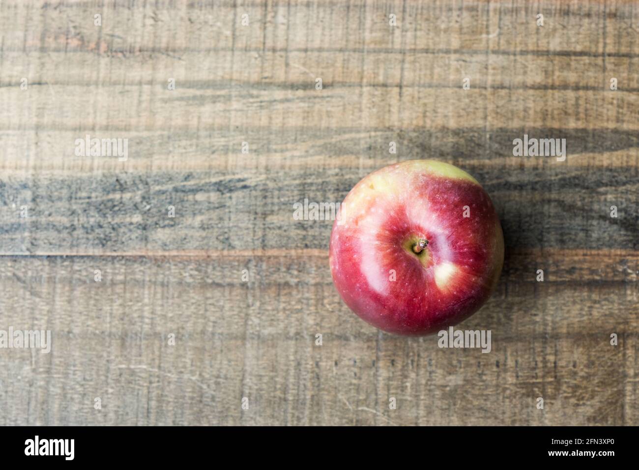 One fresh red apple on a wooden tabletop top view Stock Photo - Alamy