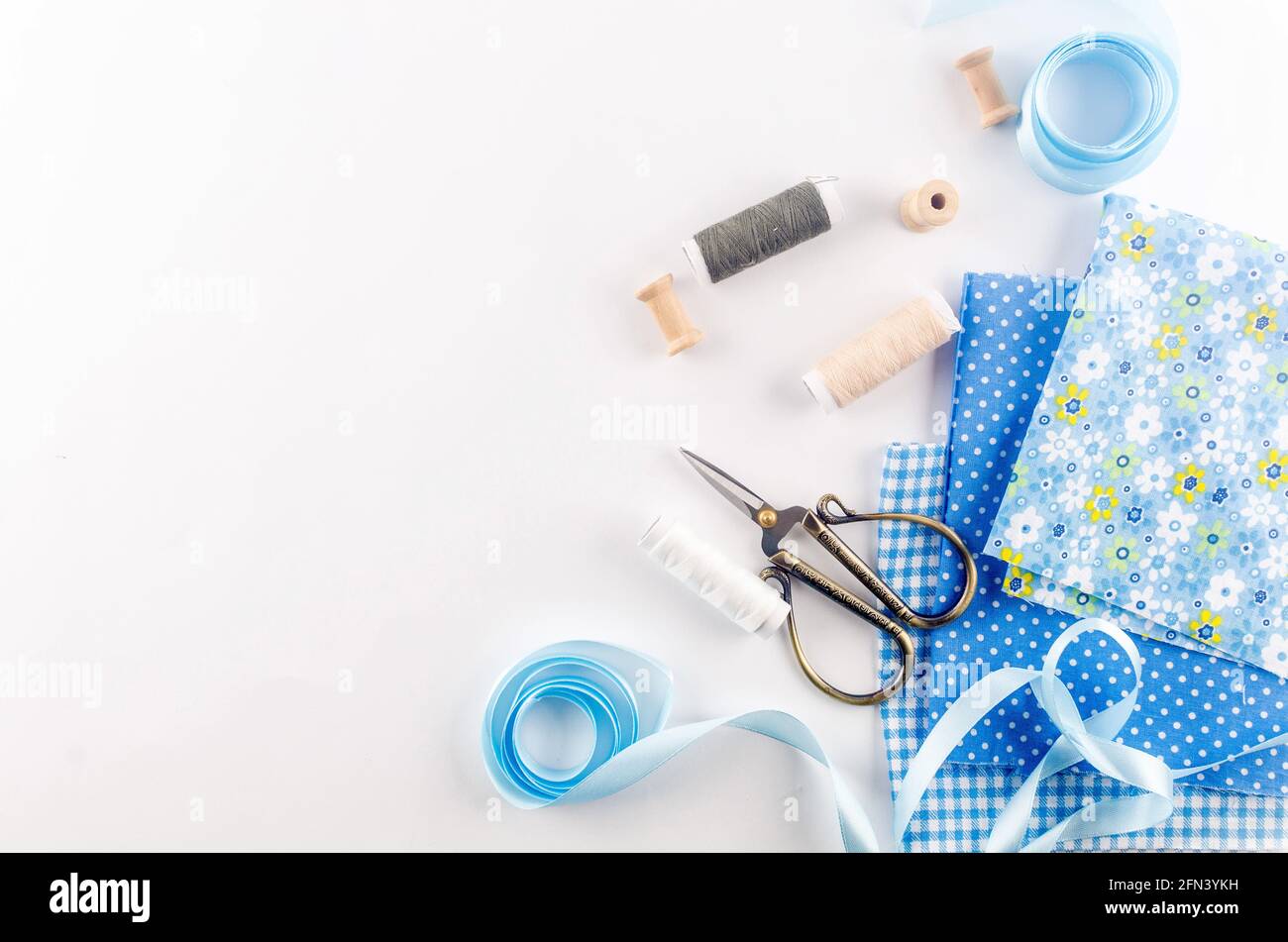 Set of blue sewing thread fabrics, buttons and accessories on a white ...