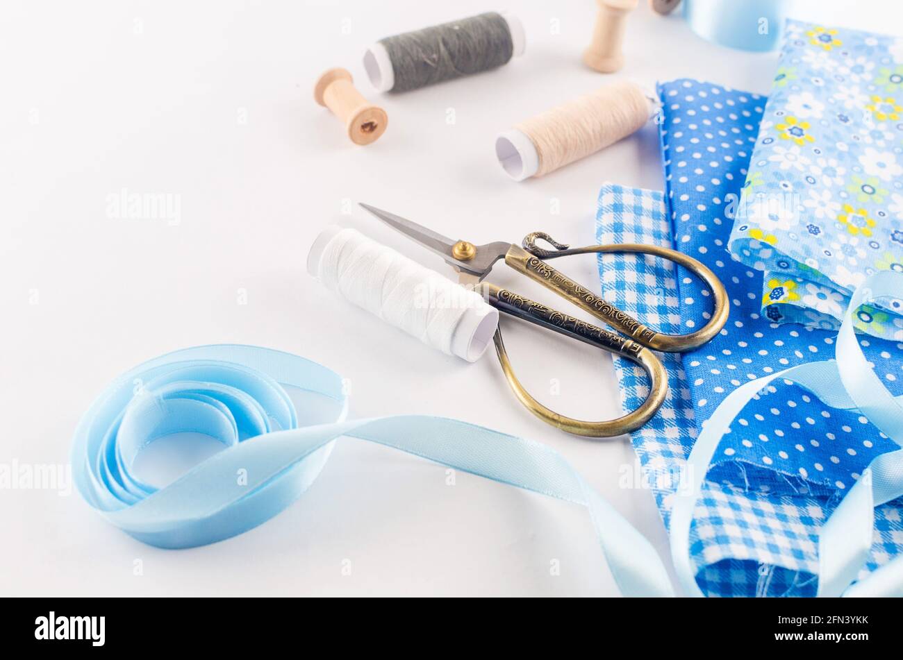 Set of blue sewing thread fabrics, buttons and accessories on a white ...