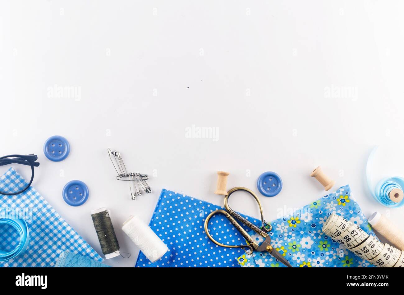 Set of blue sewing thread fabrics, buttons and accessories on a white ...