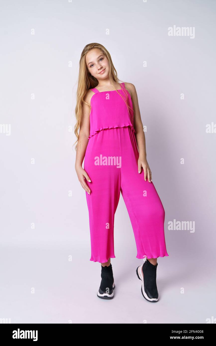 Beautiful girl teenager posing in a pink jumpsuit on a white background ...