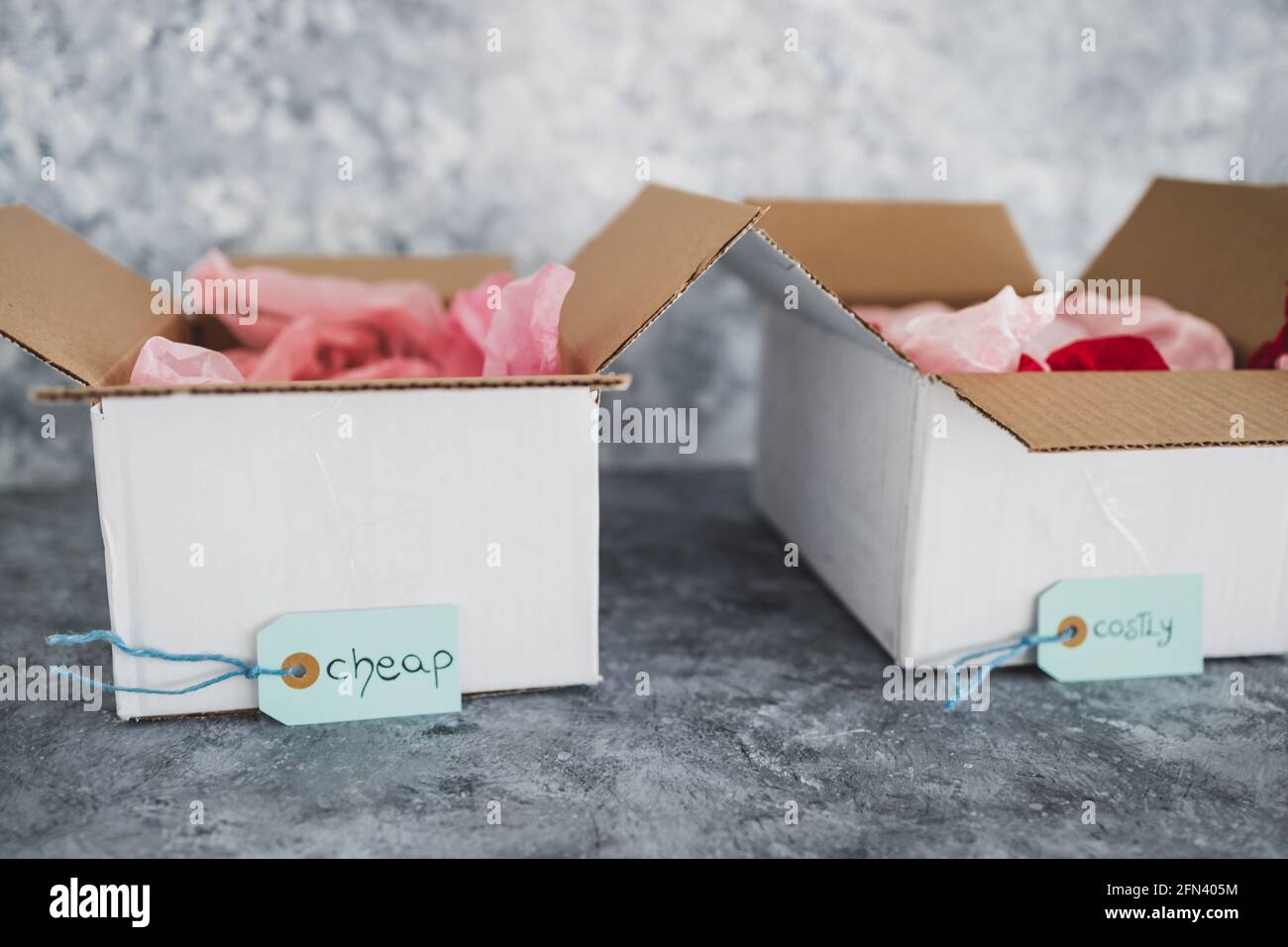 Cheap vs Costly product price tags in two delivery parcels next to each ...
