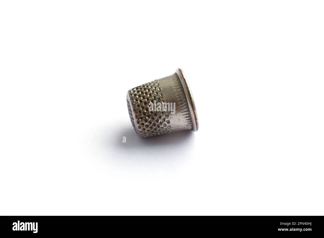 Sewing tools. An antique thimble lies on its side isolated on a white ...