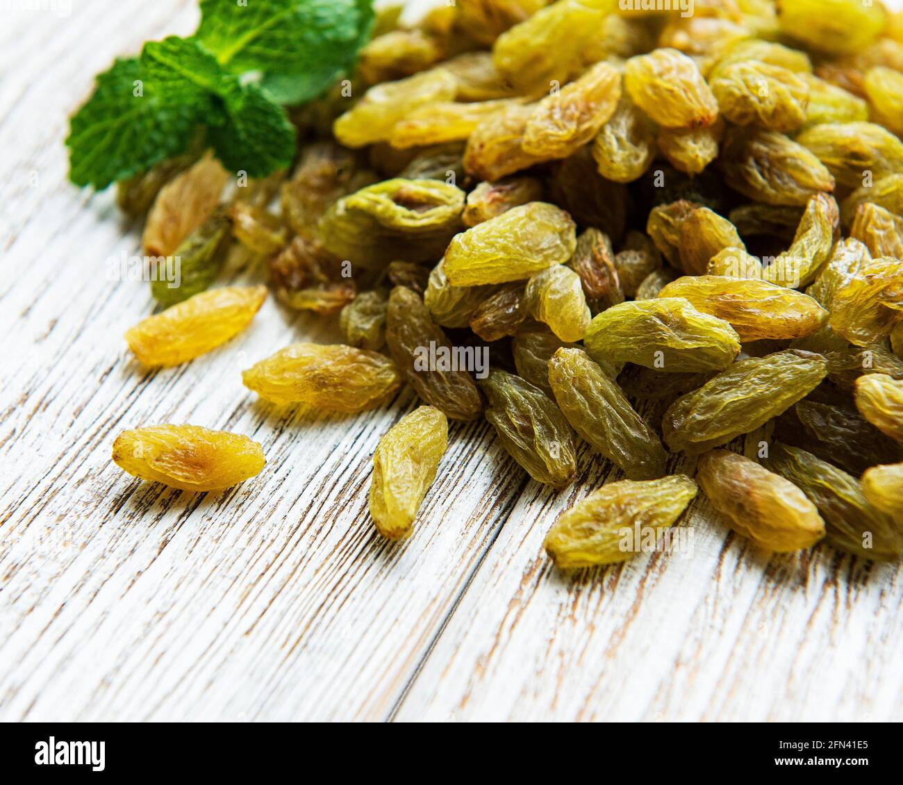 Green dried raisins on a white wooden background Stock Photo - Alamy