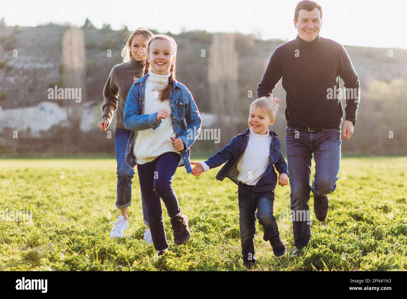 Happy family runs across the field. Father, mother and children run ...
