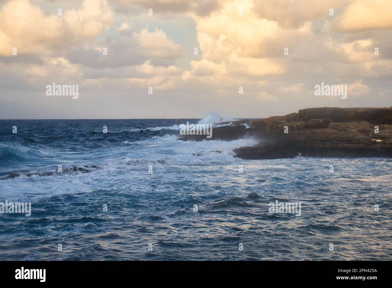 Water crashing and spraying over rocks on a beach in Qawra, Malta at ...