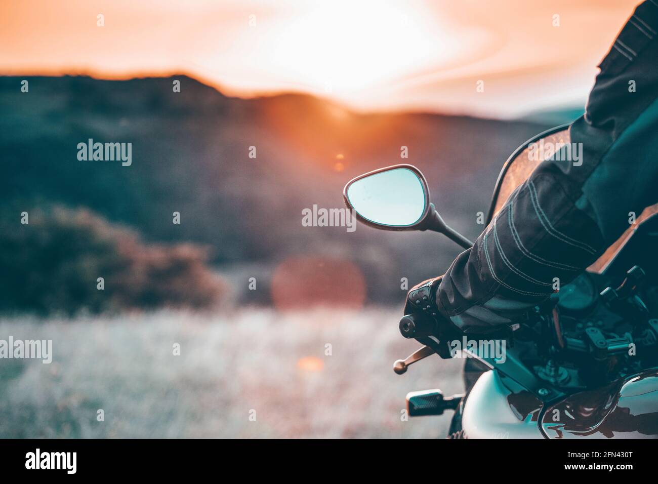 Motorbiker holding steering bar, riding in beautiful sunset. Travel and ...