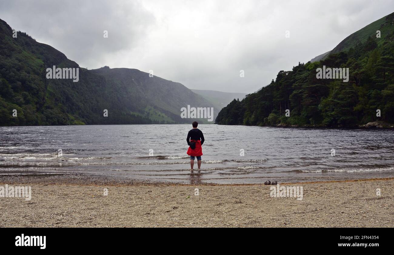 Lonely man admires the vastness of an Irish lake. Tourist photographed ...