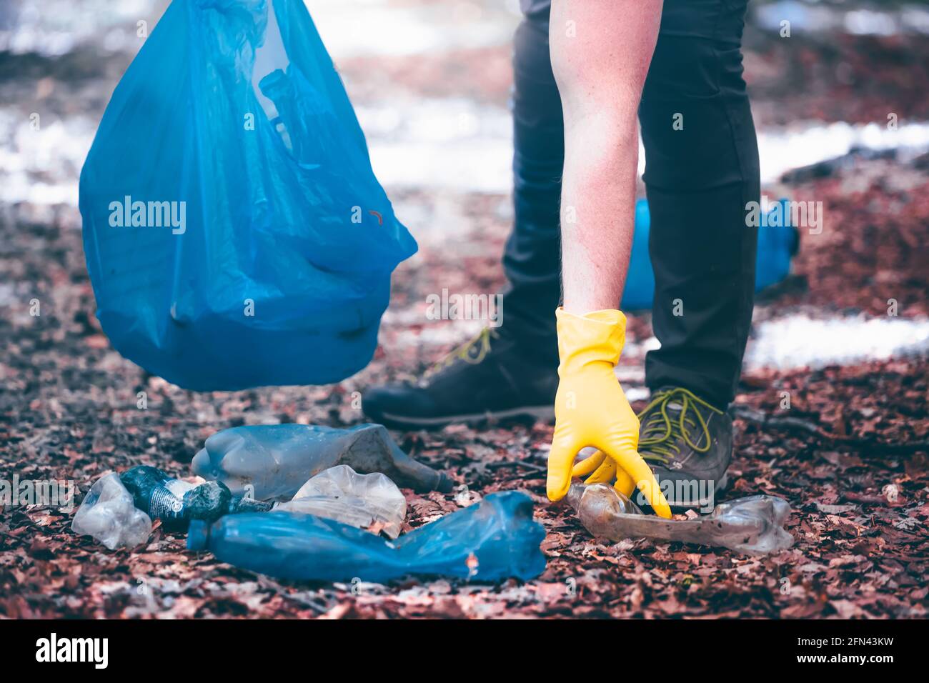 Hand picking up garbage plastic for cleaning the woods or parks ...