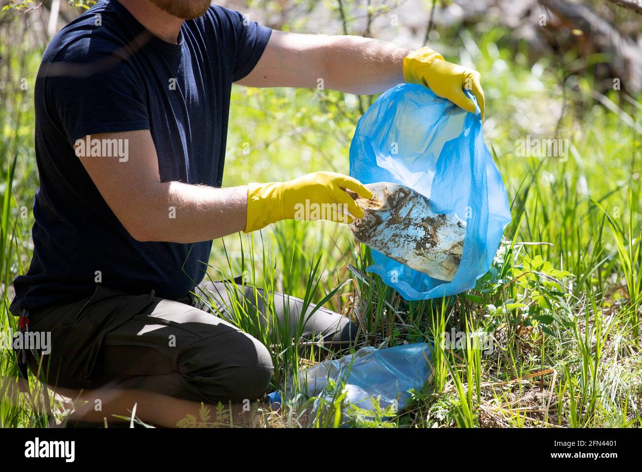 Hand picking up garbage plastic for cleaning the woods or parks ...
