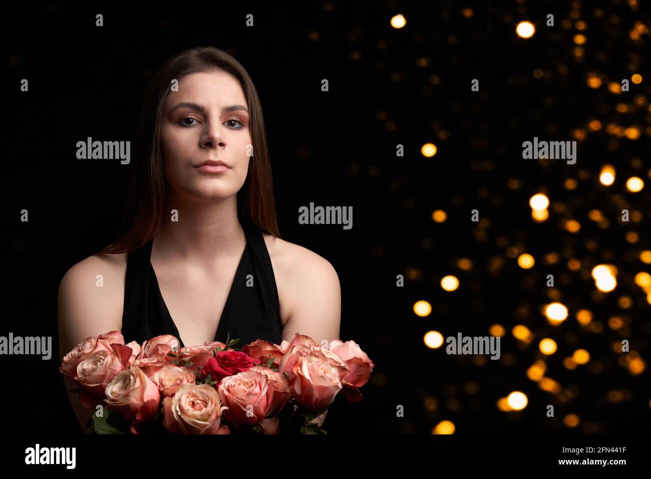 Teenage girl holding bunch of pink roses on black background isolated ...