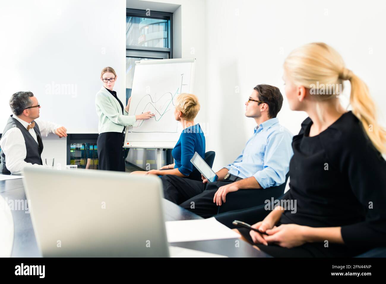 Business - presentation within a team, a female colleague is standing ...