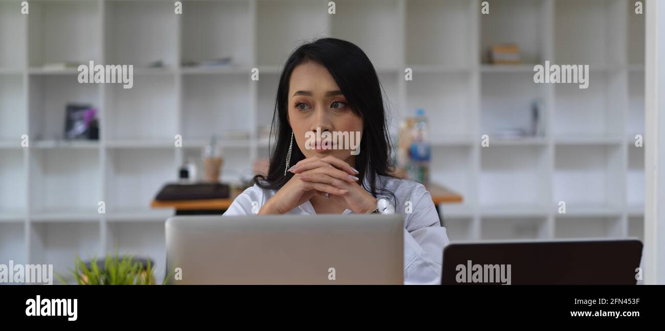 Portrait of female office worker thinking about her work while sitting ...