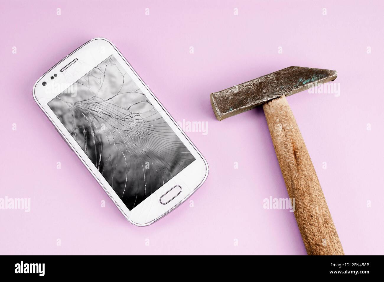 A cell phone with smashed LCD screen and a hammer on purple background ...