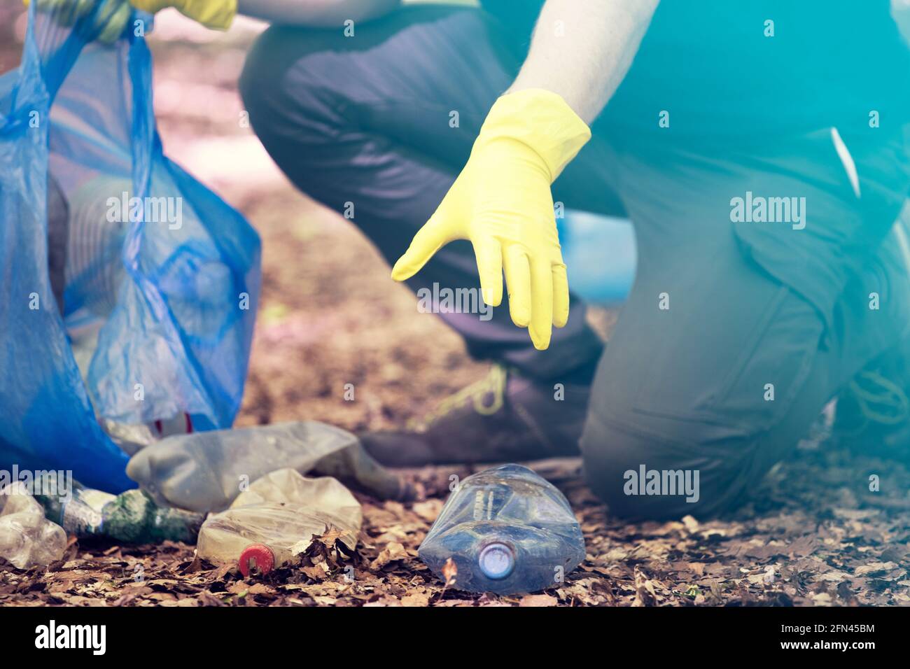 Hand picking up garbage plastic for cleaning the woods or parks ...