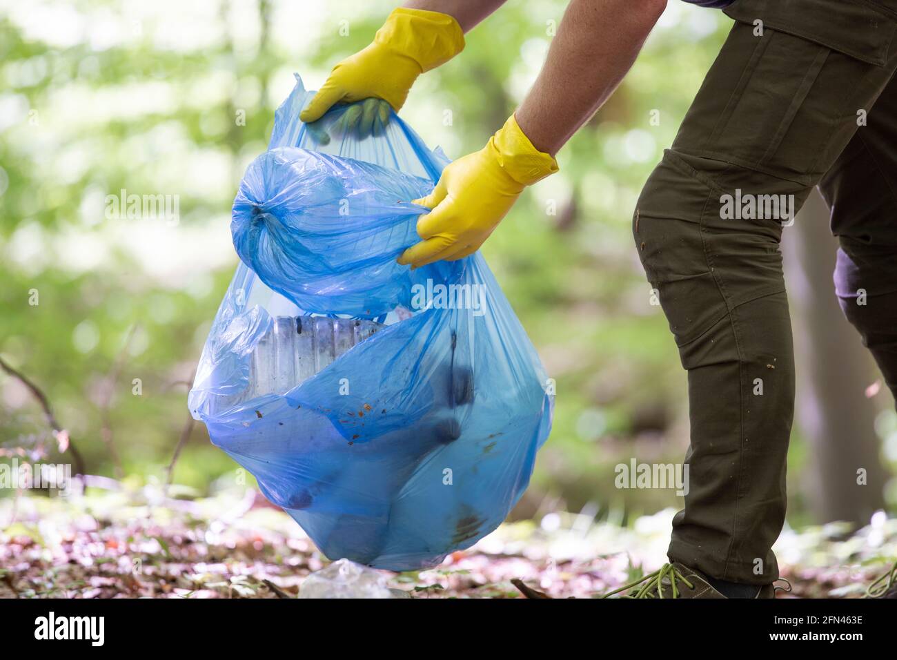 Hand picking up garbage plastic for cleaning the woods or parks ...