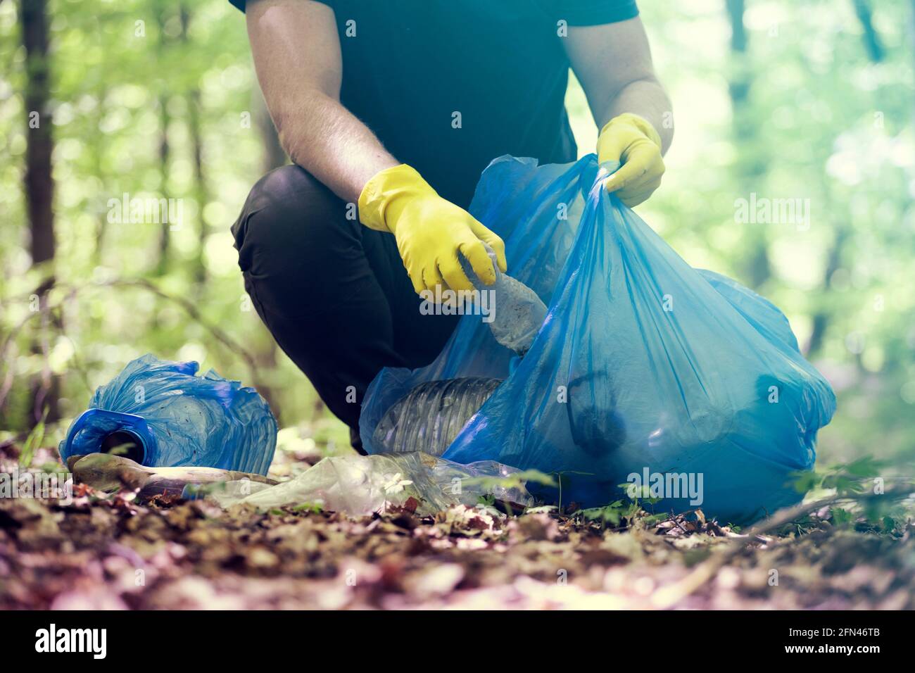 Hand picking up garbage plastic for cleaning the woods or parks ...