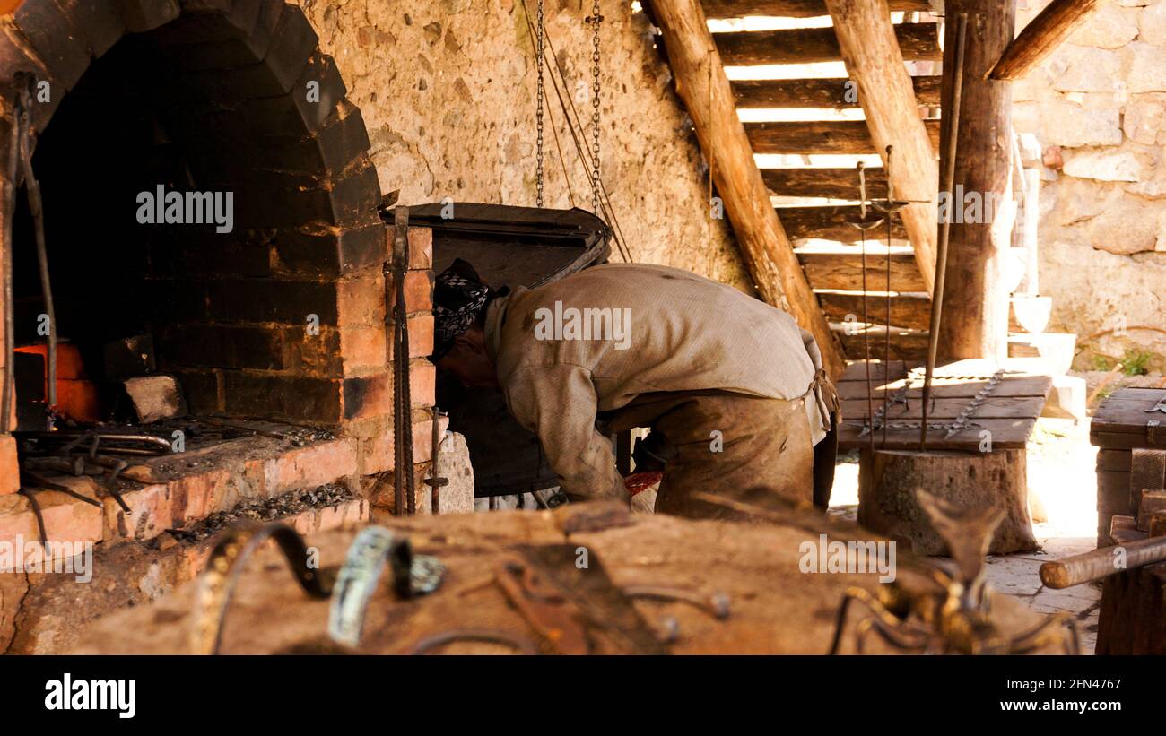 A blacksmith in an authentic workshop. Blacksmithing in the village ...